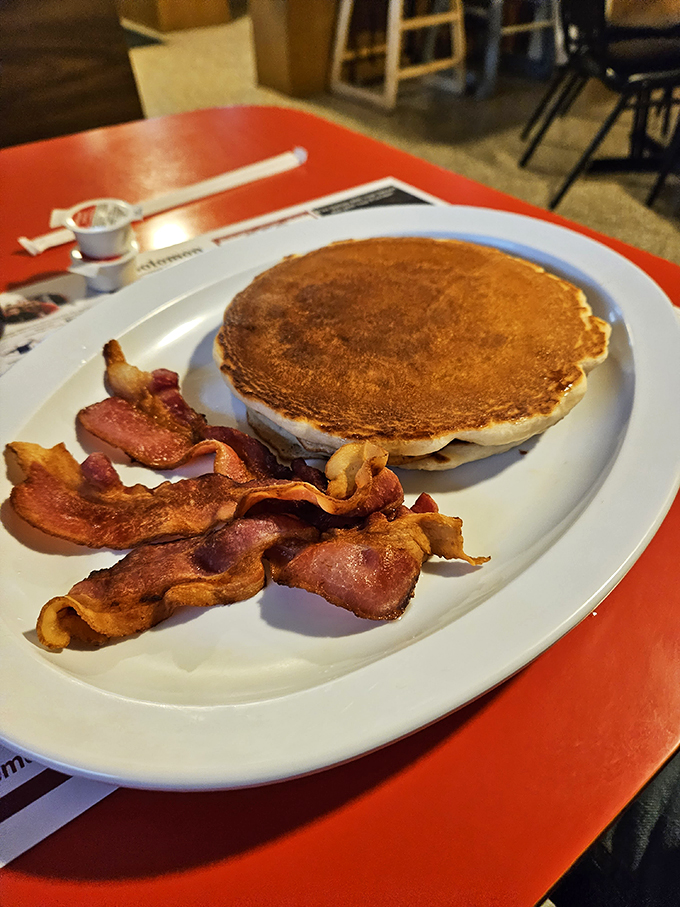 The pancake-to-bacon ratio here demonstrates perfect breakfast harmony &ndash; a golden disc of comfort flanked by crispy strips of happiness.