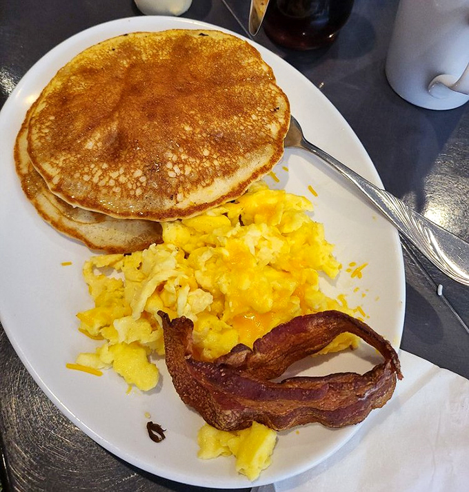 Pancakes so perfectly golden they belong in Fort Knox, with eggs and bacon that remind you why breakfast will always be the superior meal.