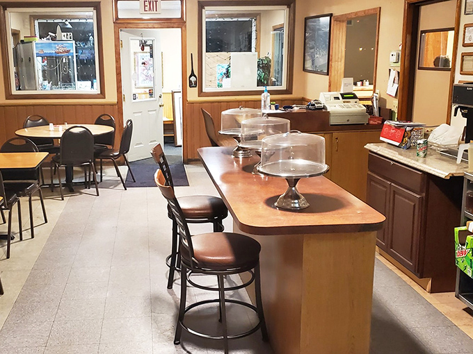 The counter seating offers front-row tickets to the quiet efficiency of a small-town restaurant. Those cake stands aren't just storage&mdash;they're pedestals for upcoming joy.