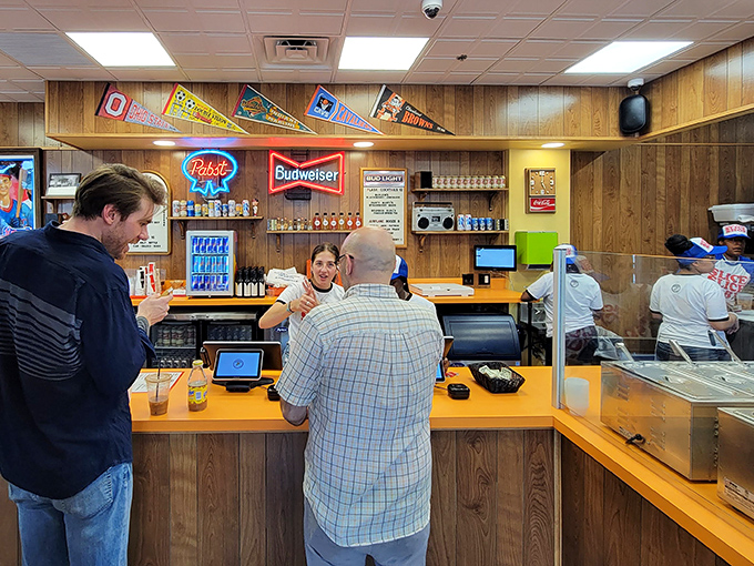 The counter where pizza dreams come true, complete with friendly faces and Ohio sports pennants watching from above.