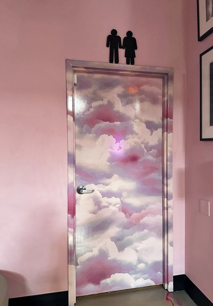 Even the restroom door transcends the ordinary&mdash;dreamy clouds painted in cotton candy hues promise a moment of zen in an unexpected place.