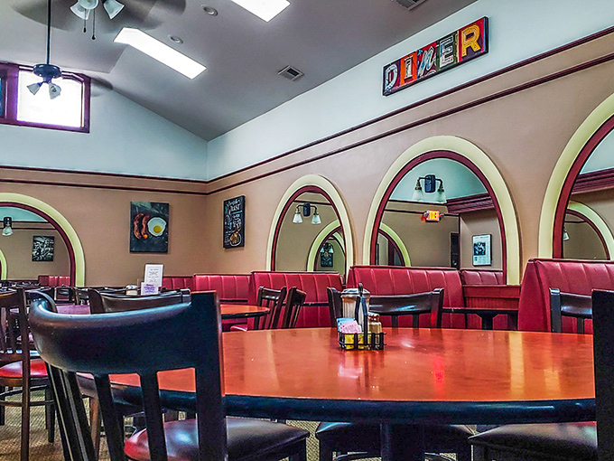 Architectural arches frame the dining experience like a stage. Red booths and round tables set the scene for breakfast theater.