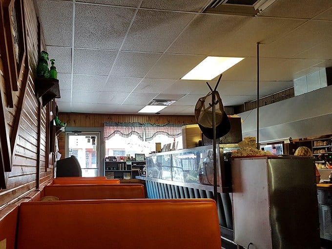 Orange booths line the wall beneath wood paneling, creating that perfect small-town diner atmosphere where everyone feels instantly at home.