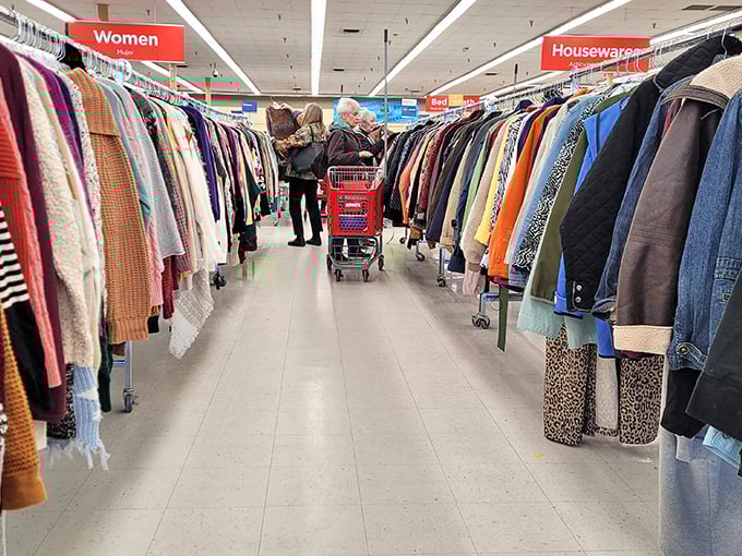 Serious shoppers navigate the clothing forest with practiced precision. The red cart means business&mdash;this isn't amateur hour in the thrift shopping leagues.