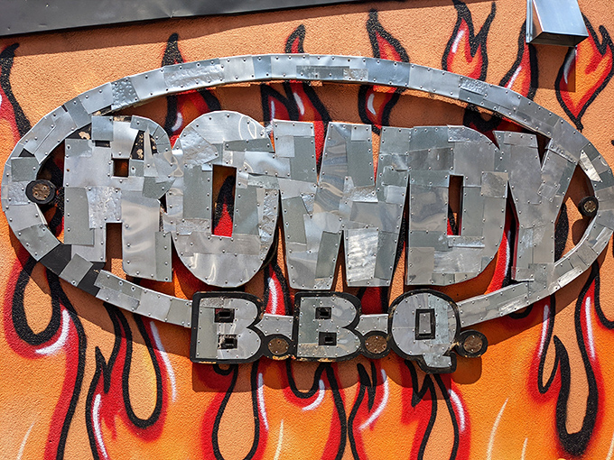 The metal Rowdy BBQ sign against flames is like a bat signal for hungry people. When you see this, your taste buds know they're about to have a very good day.