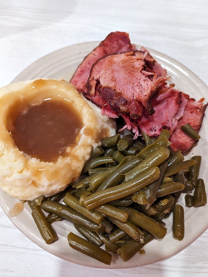 Tender ham, garden-fresh green beans, and mashed potatoes with gravy &ndash; the holy trinity of Midwest comfort that feels like a warm hug on a plate.