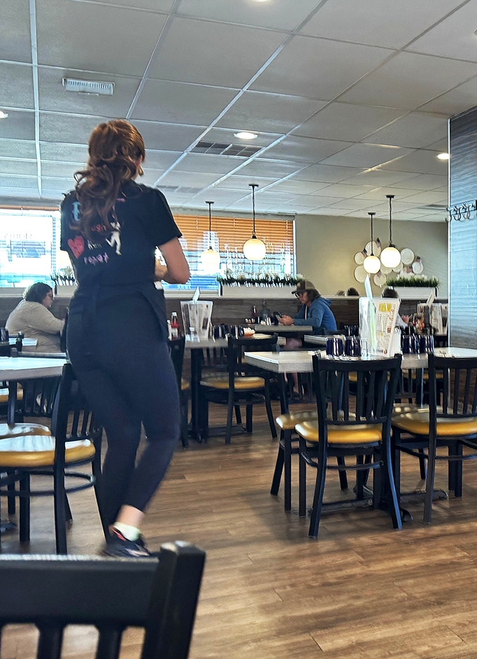 The server moves through the dining room like a breakfast ballet dancer—graceful, purposeful, and carrying the morning's salvation.