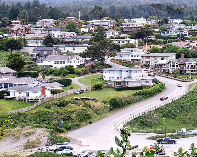 The village spreads across the headland like a model train set, each home positioned for maximum "I can't believe we live here" bragging rights.