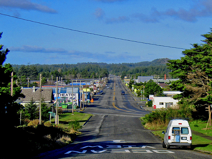 Coastal breezes meet you in Port Orford, where a long road leads your eye past charming local shops toward evergreen forests.