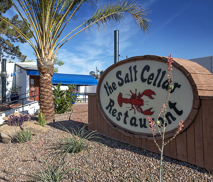 The Salt Cellar's whimsical lobster sign and desert landscaping create intrigue about underground dining adventures.