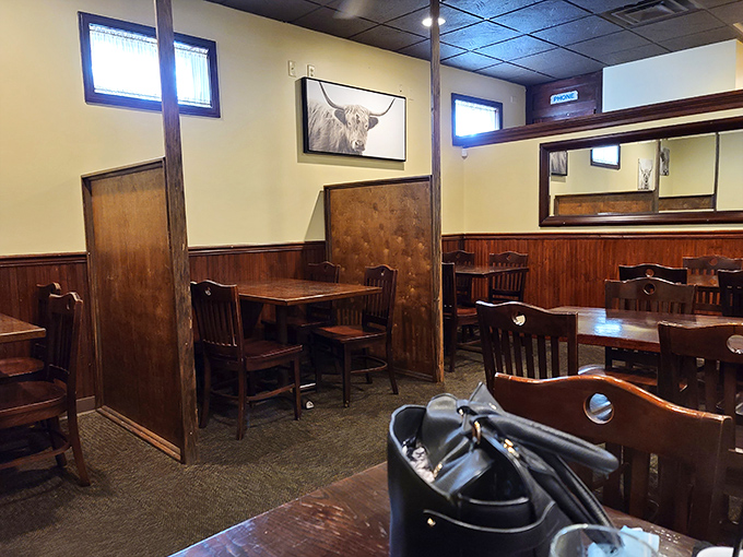 Wood paneling and comfortable seating create dining nooks that feel like your own private steakhouse. The highland cow artwork watches approvingly over your meal choices.