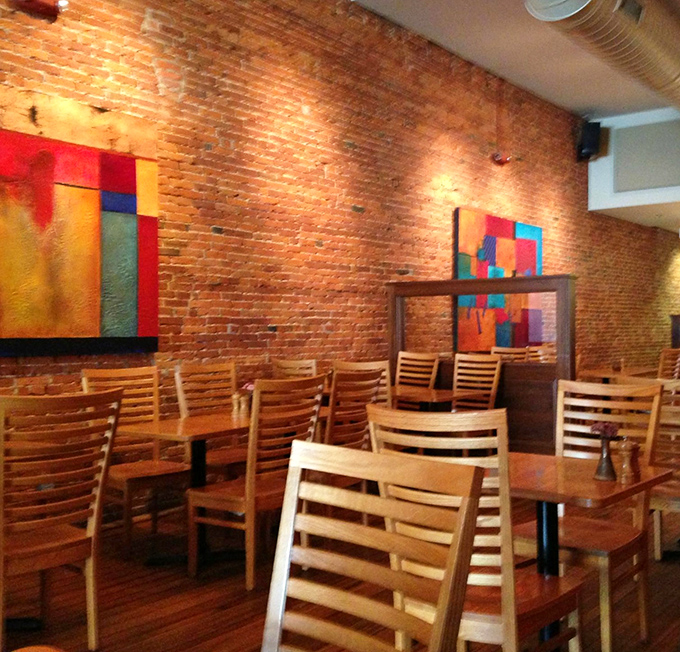 Wooden chairs that invite you to settle in for the long haul. The vibrant artwork provides a perfect counterpoint to those rustic brick walls.