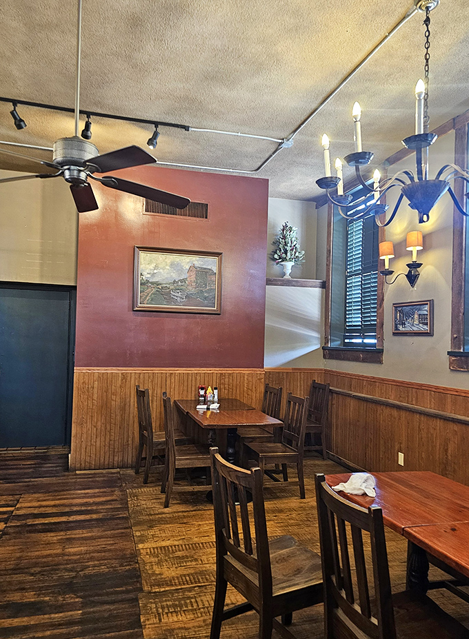 Burgundy walls, wooden wainscoting, and simple chandeliers create dining nooks where conversations flow as easily as the drinks.