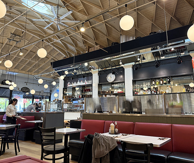 High ceilings, globe lights, and red booths create that perfect deli atmosphere where comfort and conversation flow as freely as the coffee.