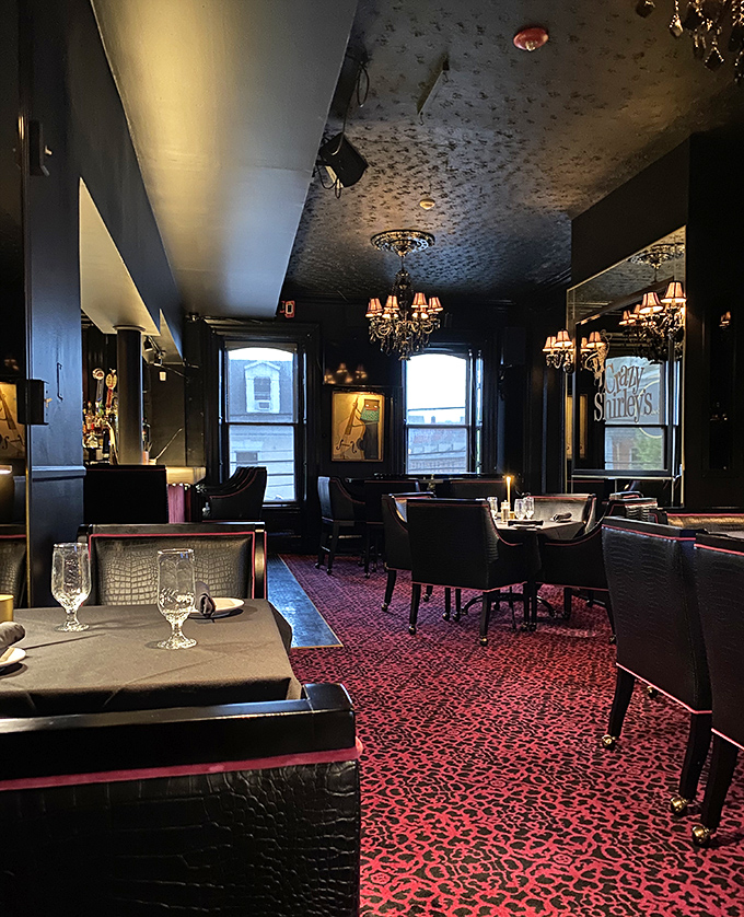 Dark walls, leopard carpet, and crystal chandeliers create a dining room that whispers "special occasion" even on a random Tuesday night.