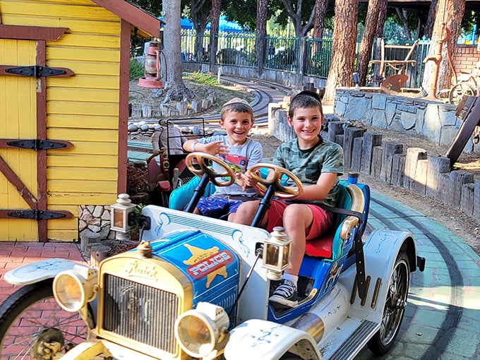 Two young drivers navigate the antique car ride with the serious concentration of rush hour commuters. Future California drivers in training!