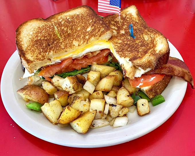 A grilled sandwich that understands the importance of balance—crispy exterior, melty interior, and those home fries looking like they've been tanned by the Florida sun.