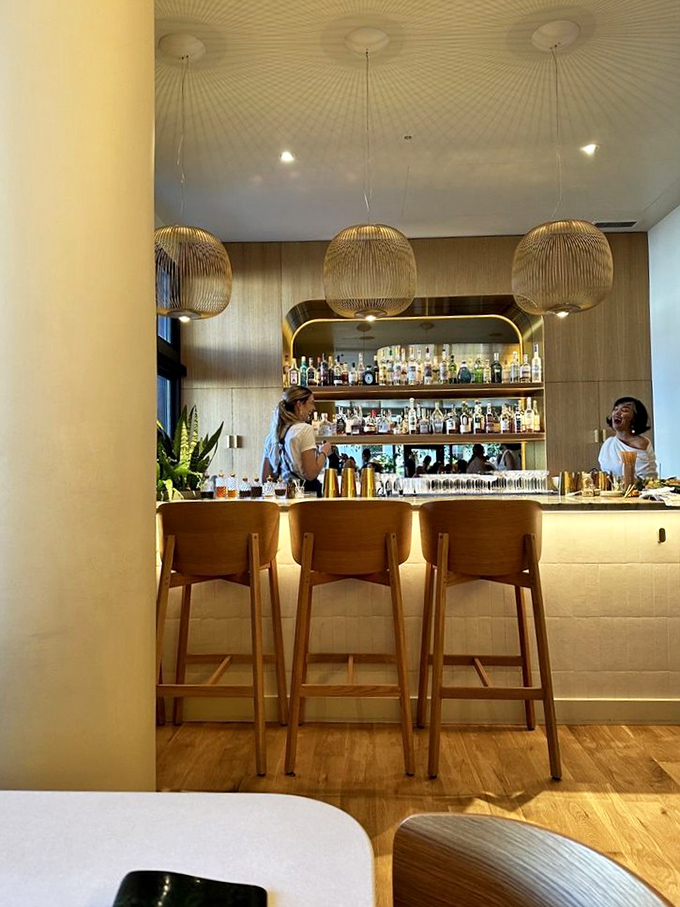 The bar at Kann doesn't just serve drinks&mdash;it creates liquid companions for your culinary journey. Golden pendant lights cast a spell of conviviality.