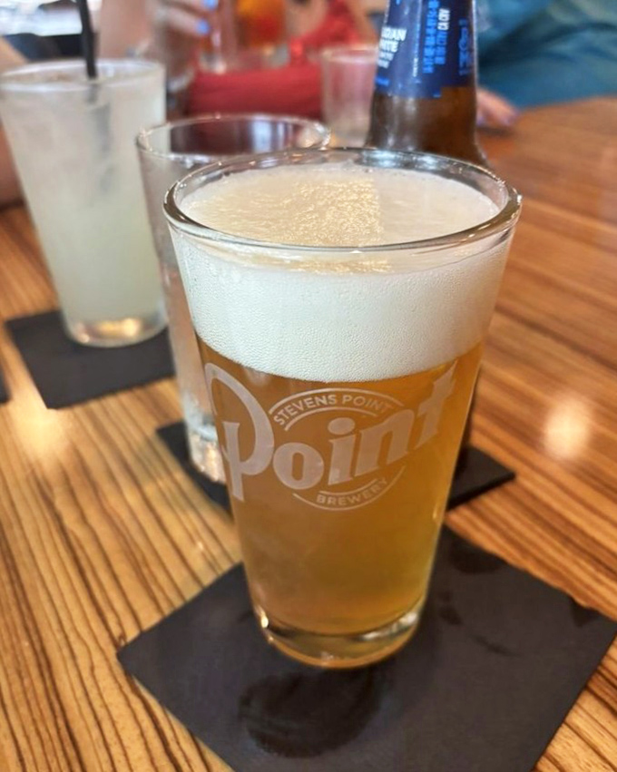 A perfectly poured Point Brewery beer catches the light like liquid amber, promising refreshment that pairs perfectly with Wisconsin cuisine.