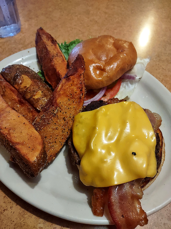 This isn't just a burger—it's architecture with cheese, nestled beside potato wedges that redefine what a spud can aspire to be.