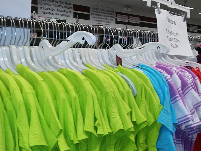 A technicolor dream of t-shirts awaits, arranged by hue like a thrifter's rainbow promising gold at either end.