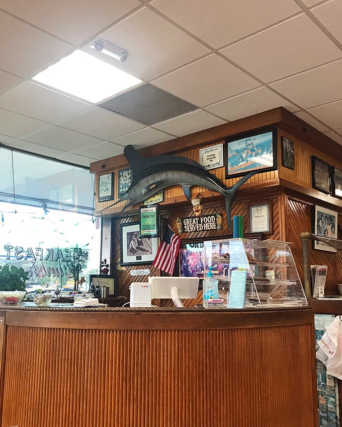 Behind the counter, where diner magic happens—note the marlin trophy watching over proceedings like the patron saint of good eating.