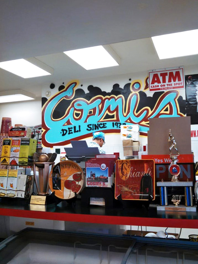 Behind the counter, where sandwich magic happens daily. The colorful mural reminds you this isn't just a deli&mdash;it's a Philadelphia institution.
