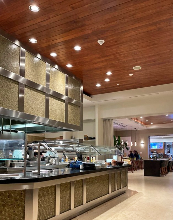 The open kitchen isn't just for show—it's culinary transparency where chefs perform their seafood symphony under warm wood ceilings and golden lighting.