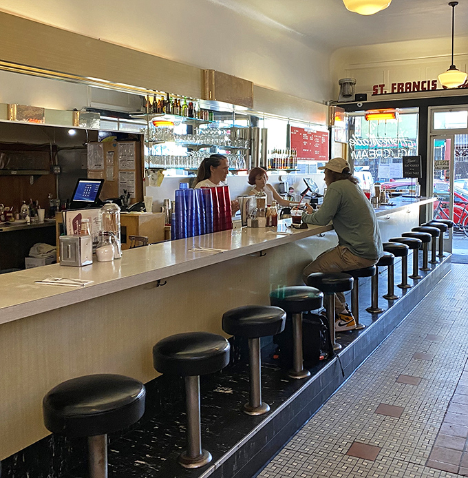 The counter stretches like a runway for comfort food, where black stools await the next hungry patron and conversations flow as freely as the coffee.