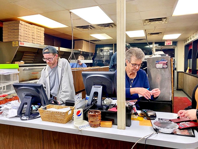 Behind the counter, the heart of Giovanni's operation. Where orders are called, pizzas are boxed, and decades of service continue without fanfare.
