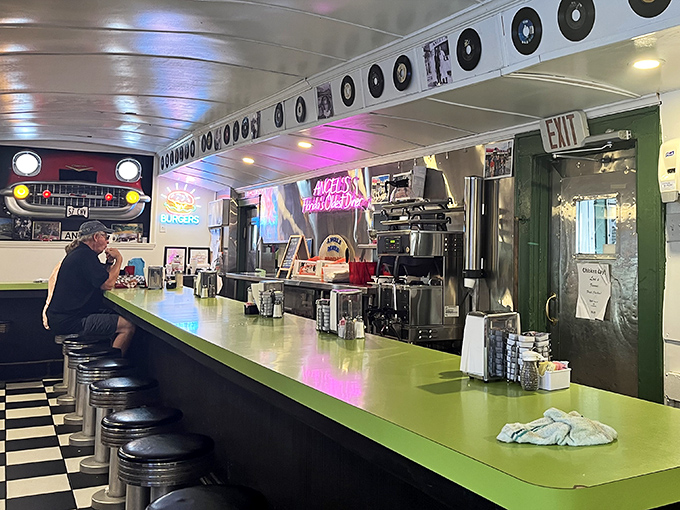 The long counter where solo diners find community, watching short-order magic happen while vinyl records keep watch from above like culinary guardian angels.