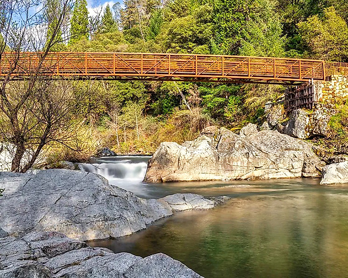 Deer Creek's crystal waters flow beneath a wooden footbridge, creating a scene so perfectly serene it could be mistaken for a painting.