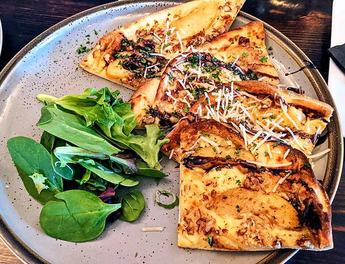This flatbread isn't just a pizza's sophisticated cousin &ndash; it's a crispy canvas where caramelized toppings and melted cheese create edible art.
