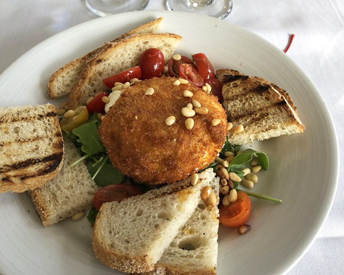 Golden fried burrata with cherry tomatoes and pine nuts creates a harmony of textures and flavors.