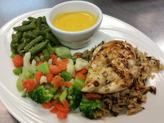 A plate that whispers "you can eat healthy here too" with grilled chicken, wild rice, and vegetables that haven't forgotten what sunshine tastes like.