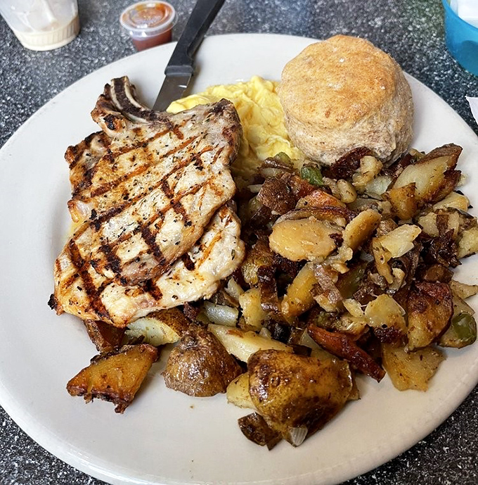 A pork chop with grill marks so perfect they deserve their own Instagram account, flanked by home fries that redefine potato perfection.