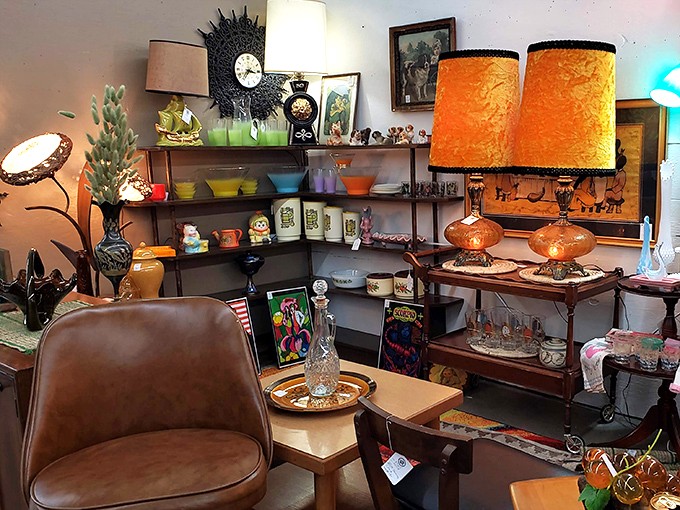 Mid-century modern meets retro kitsch in this booth where orange lamps cast a warm glow over treasures that would make Don Draper feel right at home.