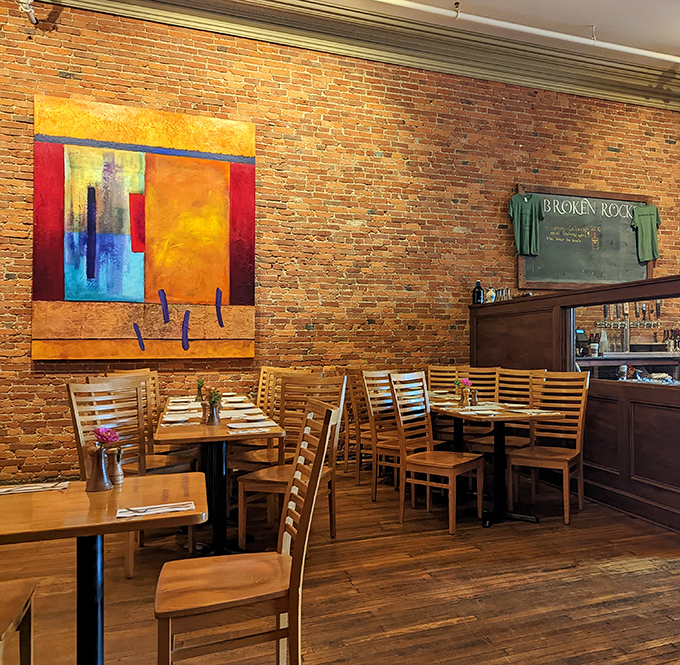 The dining room where rustic meets refined—those vibrant paintings against brick walls create the perfect backdrop for culinary memories.