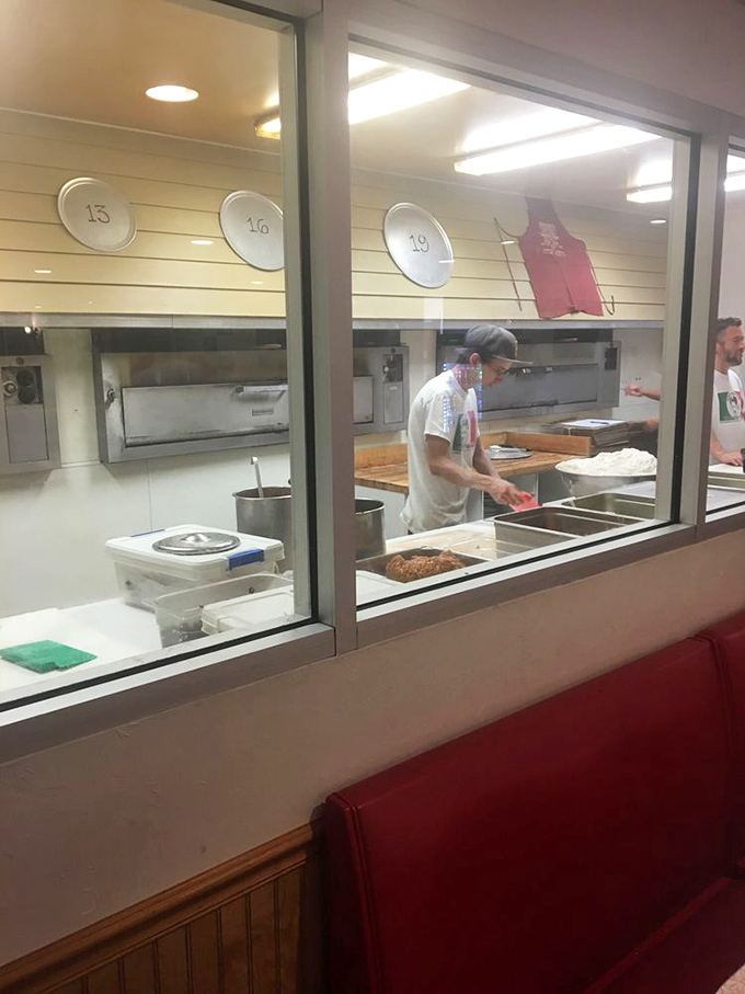 A glimpse into the pizza workshop where dough becomes legend. Those numbered plates on the wall have seen decades of pizza perfection.