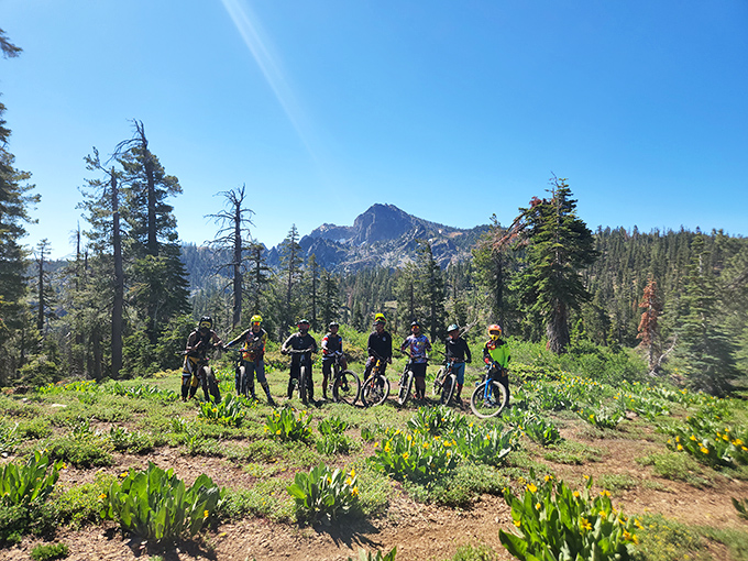 Mountain bikers pause to appreciate the view they've earned through sweat equity, with Sierra peaks creating the kind of backdrop Instagram filters try to imitate.