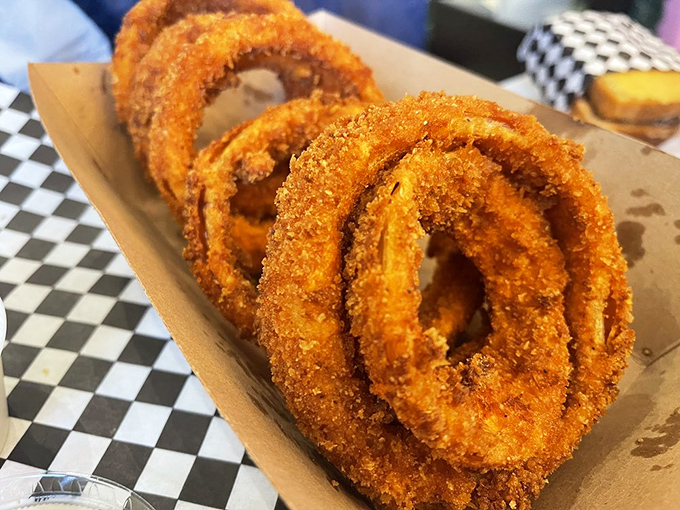Onion rings with the perfect crunch-to-tenderness ratio, nestled in a checkered paper cradle. These golden halos deserve their own fan club.