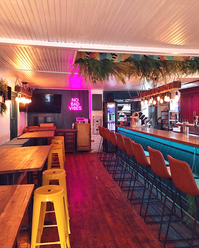 Inside, the "No Bad Vibes" neon isn't just decoration&mdash;it's a promise kept through ambient lighting and lush hanging plants that soften the industrial elements.