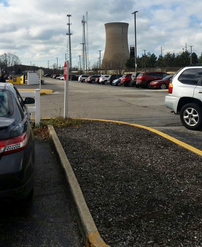 Ample parking with industrial backdrop. Nothing says "serious shopping destination" like a cooling tower on the horizon.