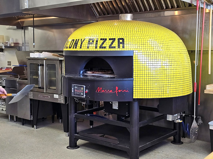 The yellow-tiled pizza oven stands like a beacon of hope in the kitchen, promising crispy-bottomed perfection with every pie.