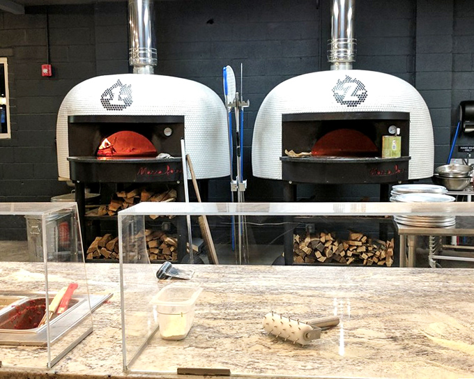 The twin wood-fired ovens stand like sentinels of flavor, transforming simple dough into blistered canvases of culinary art in mere minutes.