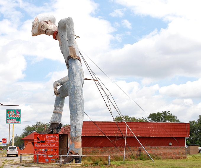 This historical photo shows Tex during restoration work, revealing the engineering marvel required to keep a concrete cowboy standing tall.