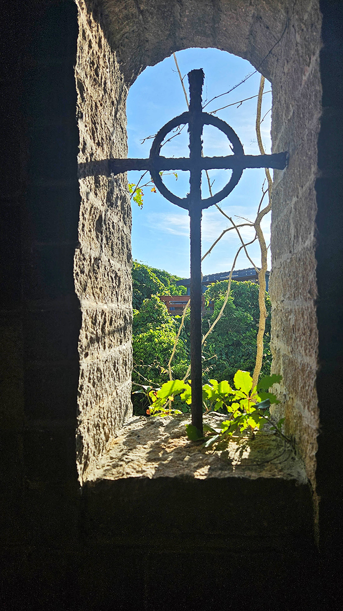 A Celtic cross framed by stone creates a contemplative moment, sunlight streaming through to illuminate both architecture and purpose.