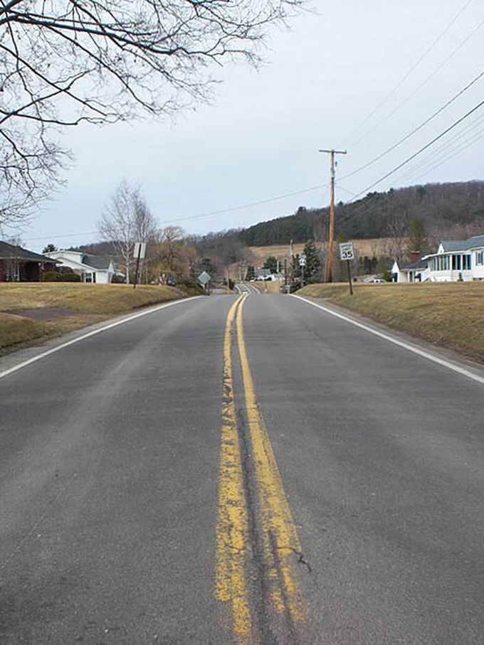 The road stretches toward distant hills like an invitation. Small-town America still exists, just follow the yellow line.