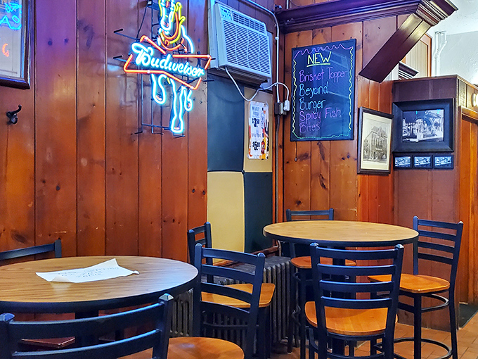 Neon signs cast their colorful glow over simple round tables, creating the perfect backdrop for both quiet conversations and boisterous celebrations.