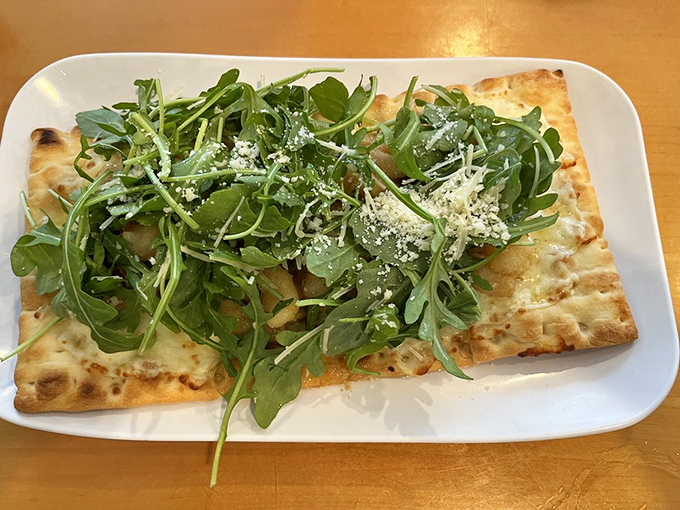 Flatbread that defies expectations with its mountain of arugula. Underneath that green canopy lies cheesy, savory perfection.